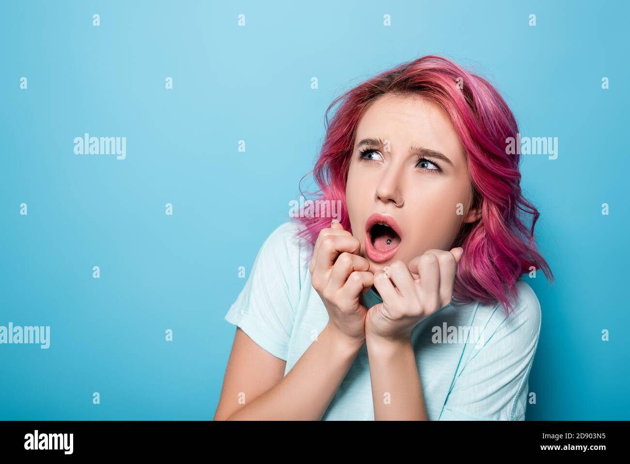 scared young woman with pink hair on blue background Stock Photo - Alamy