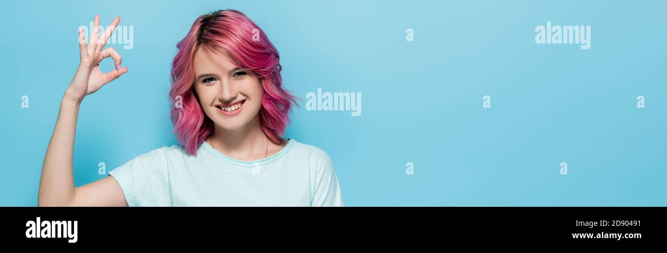young woman with pink hair showing ok sign on blue background ...