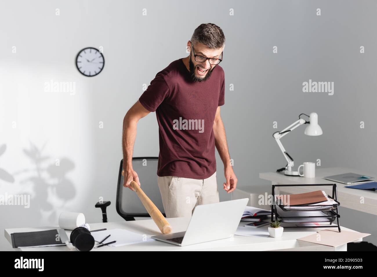 Mad businessman holding baseball bat near laptop during nervous ...