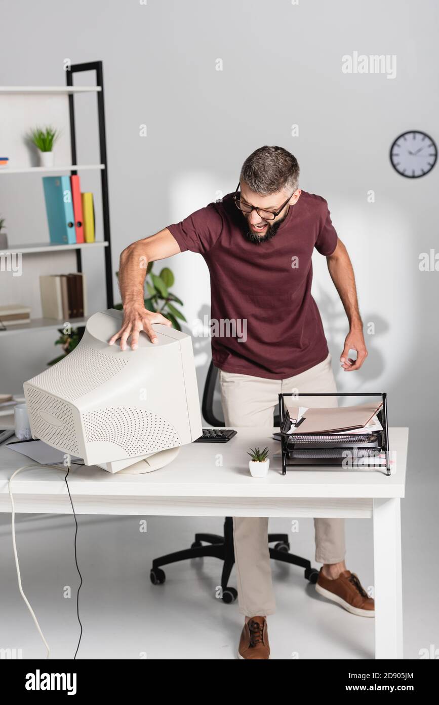 Aggressive businessman screaming while touching computer monitor near ...