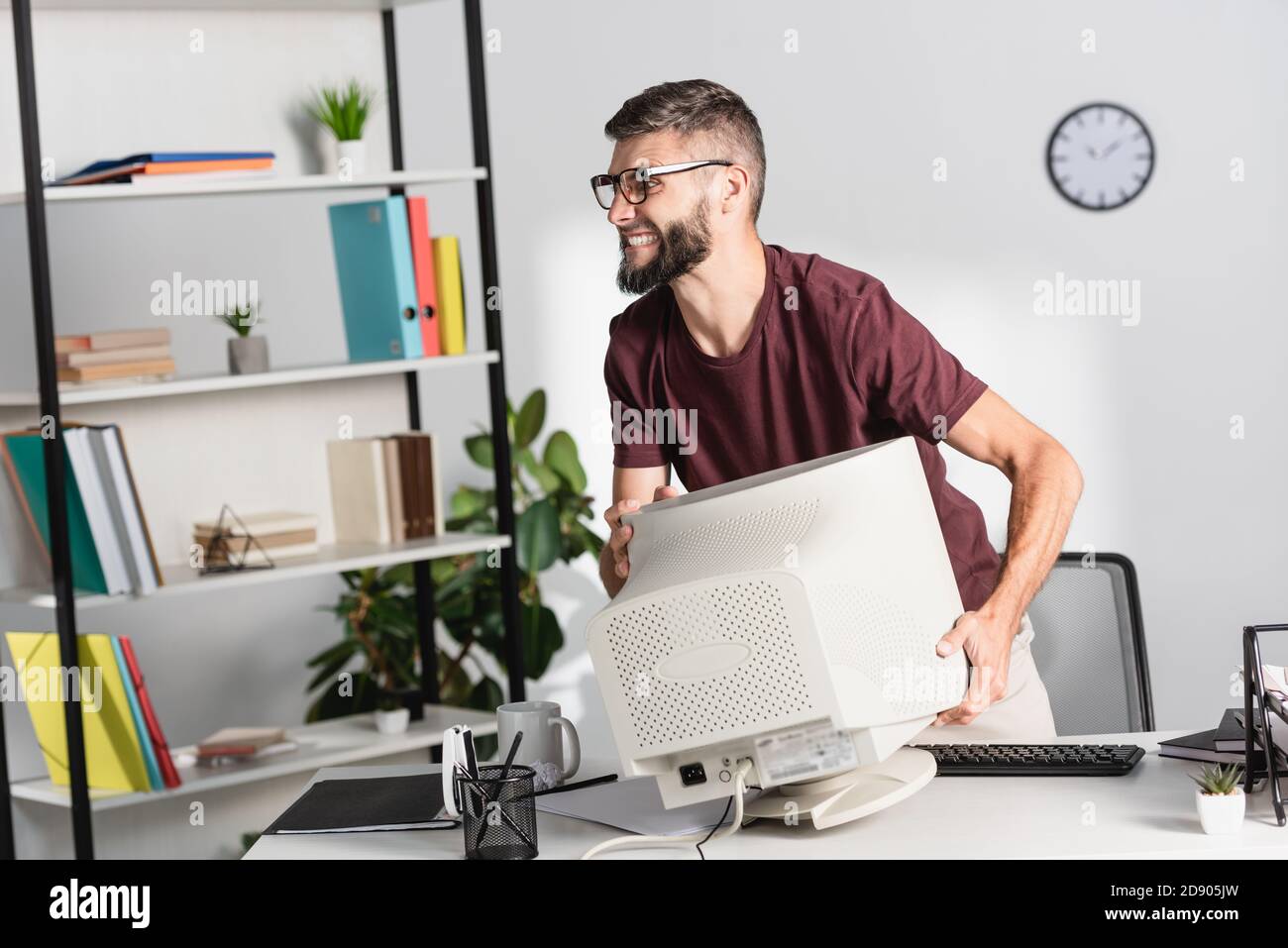 Angry businessman holding computer monitor during nervous breakdown in ...