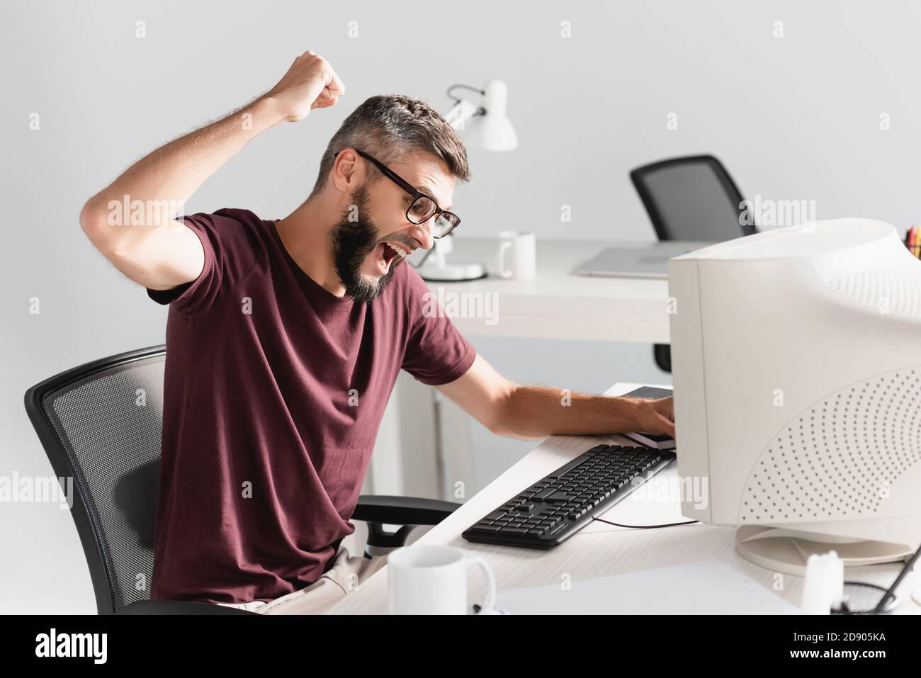 Screaming businessman sitting near computer on blurred foreground ...