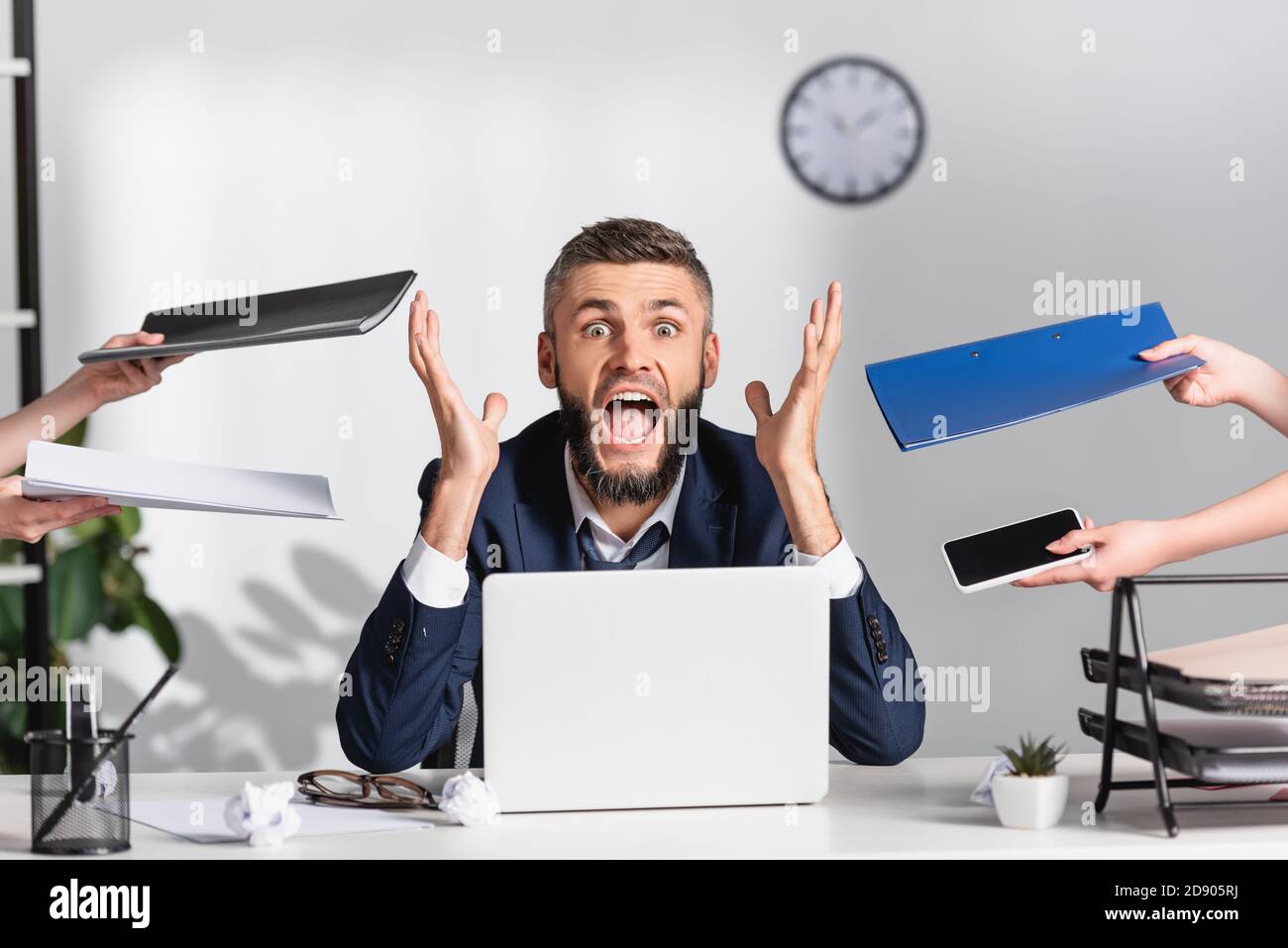 Stressed businessman screaming near colleagues with paper folders and ...