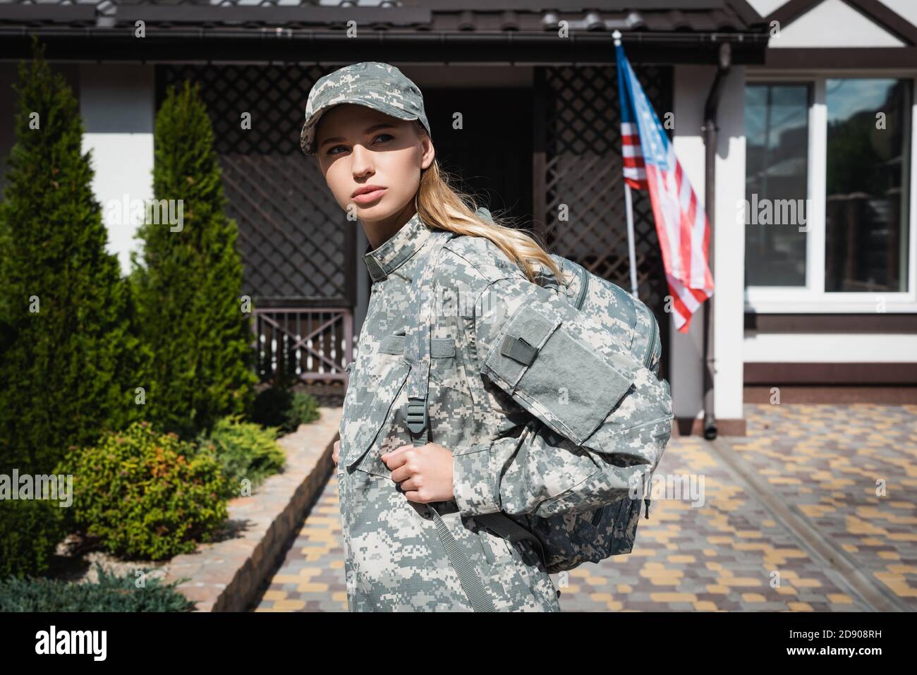 Confident military servicewoman with backpack looking away, while ...