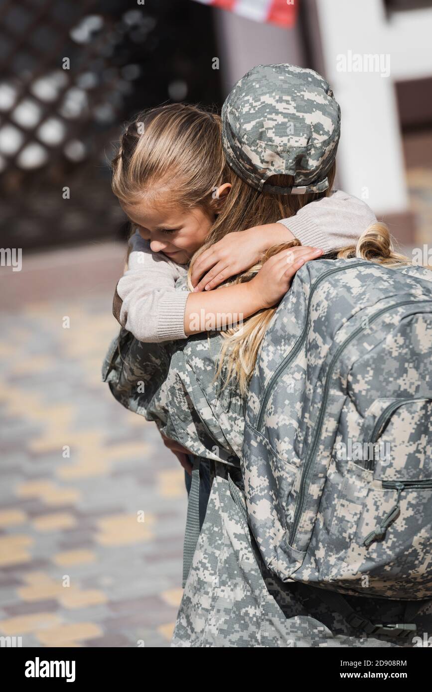 Smiling daughter hugging mother in military uniform on blurred ...