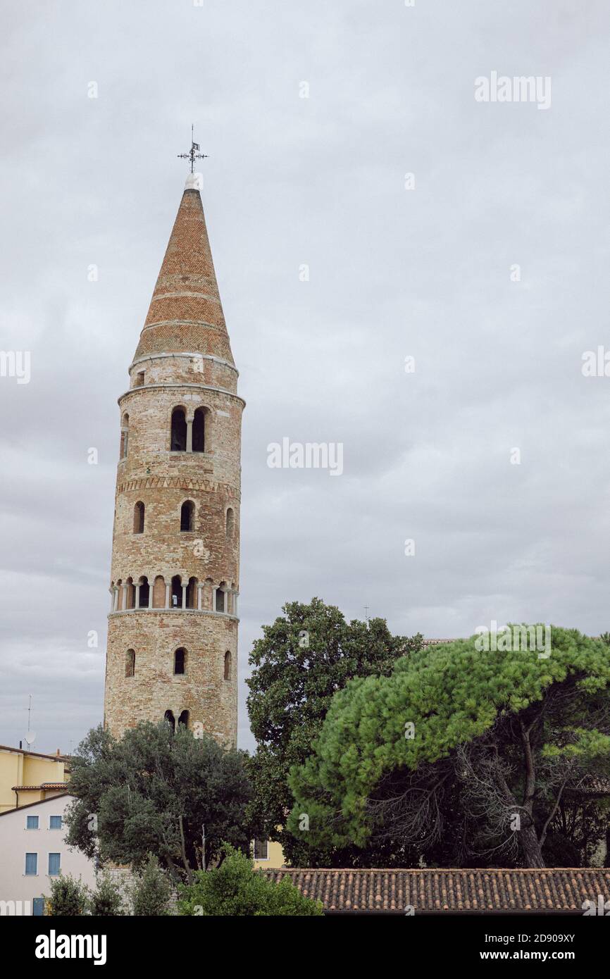 Round, medieval bell tower immersed in the clouds in Caorle, Italy ...