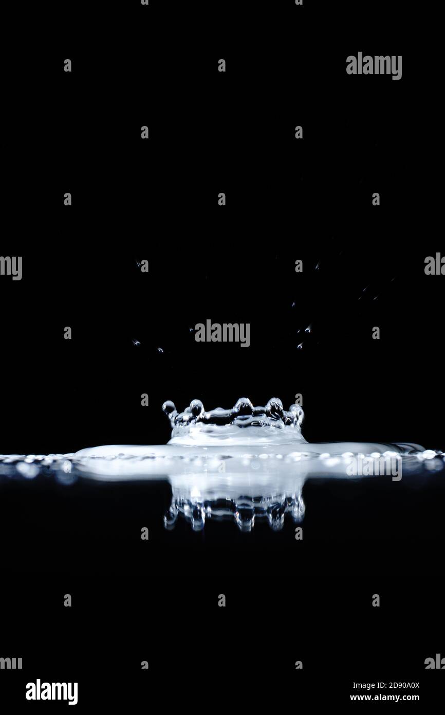Vertical closeup shot of clear water splash isolated on a dark ...