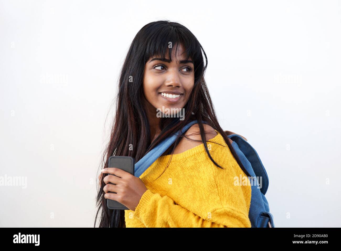 Side portrait of happy Indian female student with bag and mobile phone ...