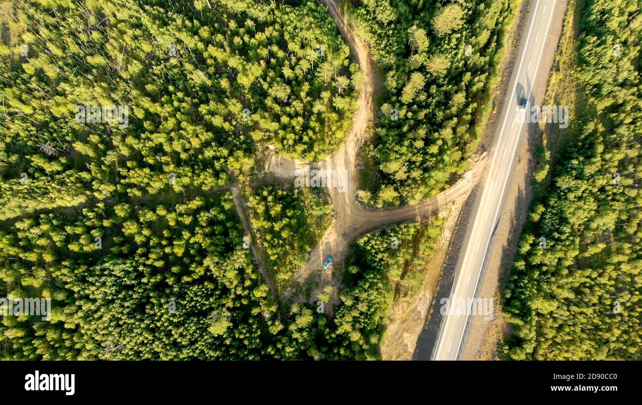 Aerial view of country road with few cars driving between forests on a ...