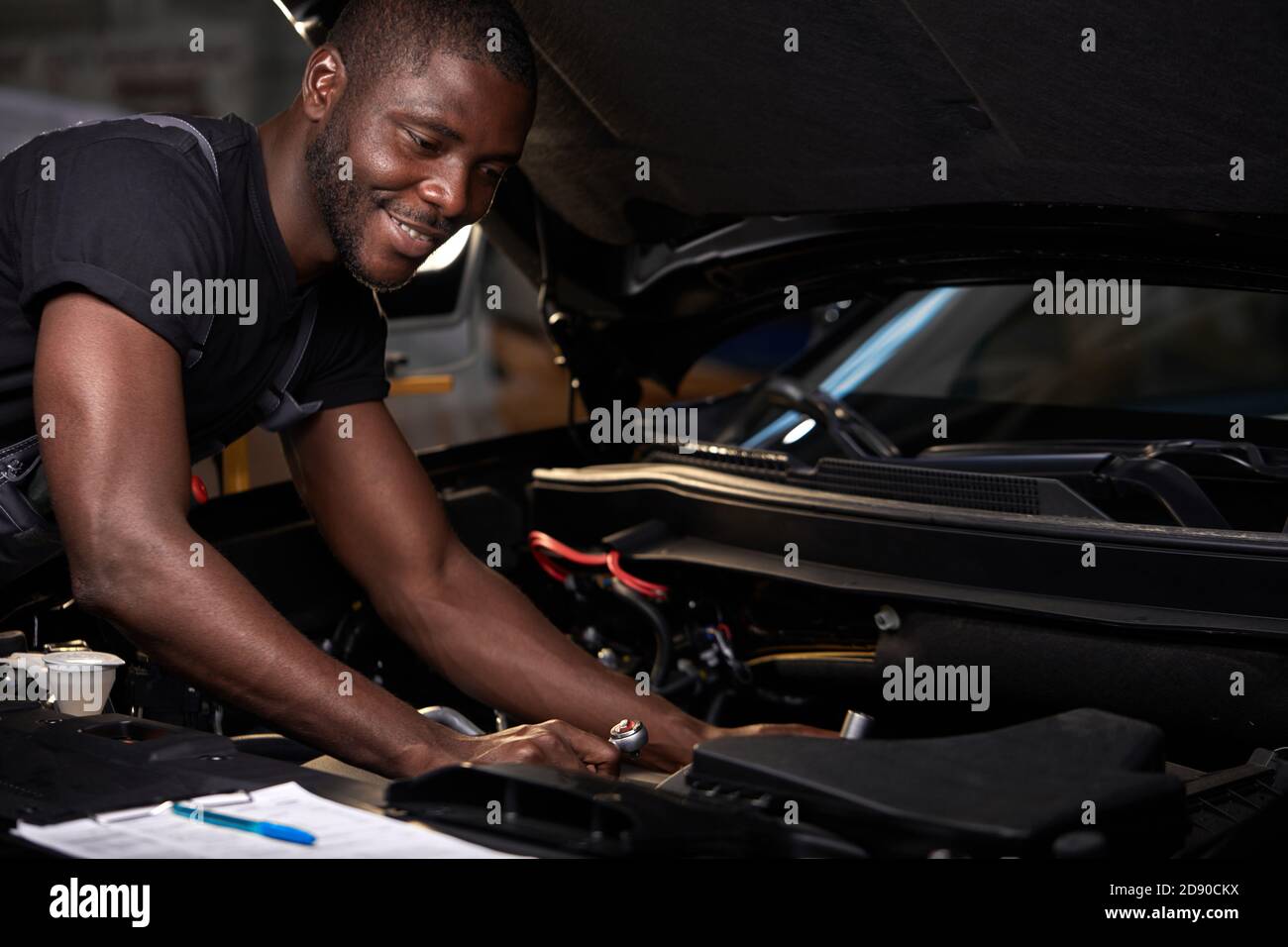 african professional auto service technician in uniform standing near ...