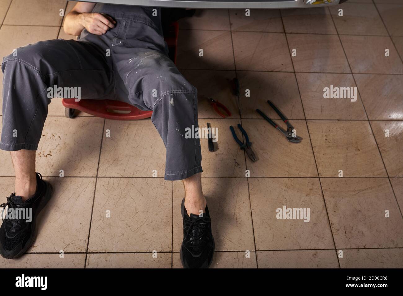 top view on legs of auto mechanic man repairing car bottom, lie on the ...