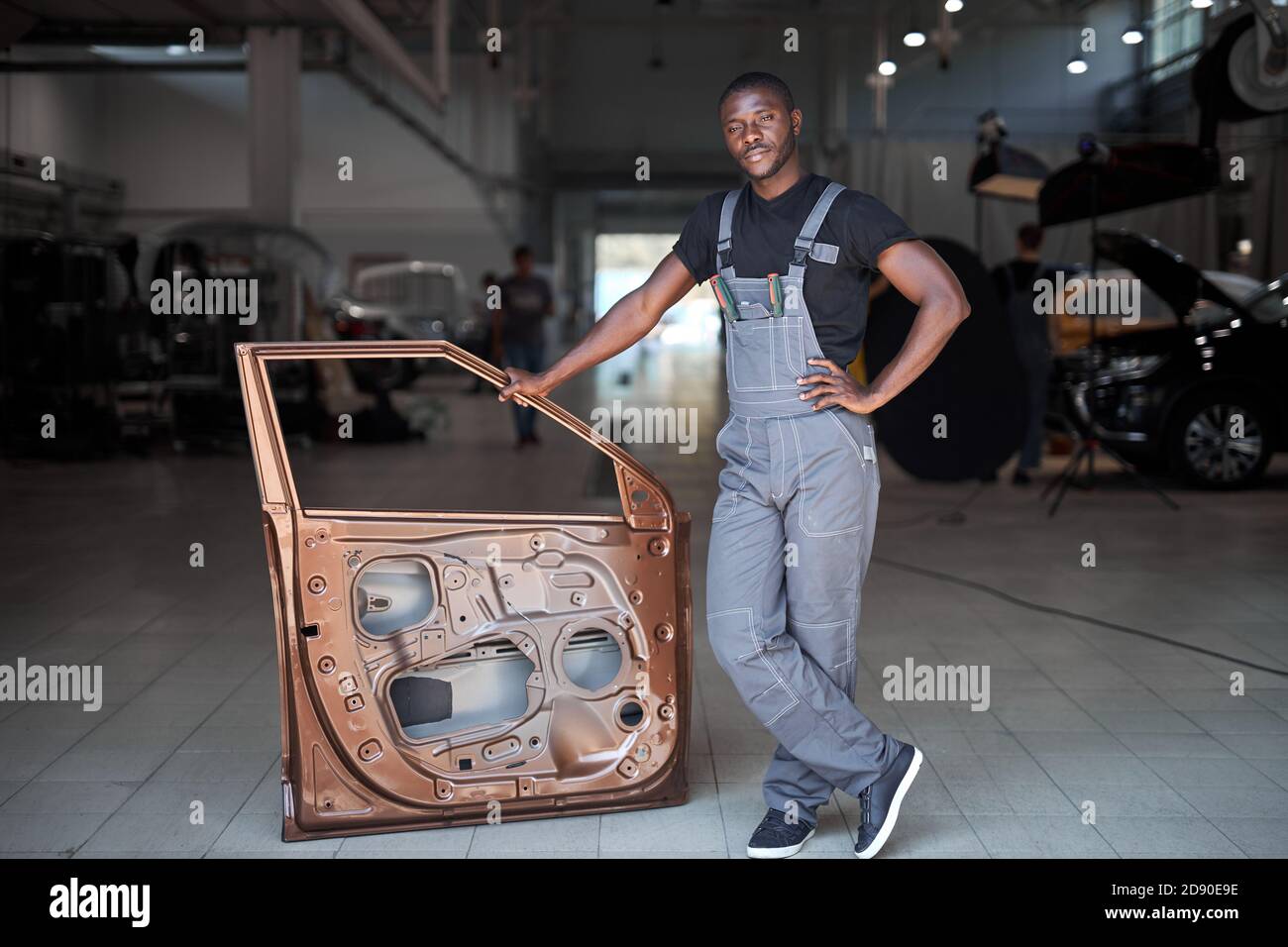 young african auto mechanic at work with separate part of the machine ...