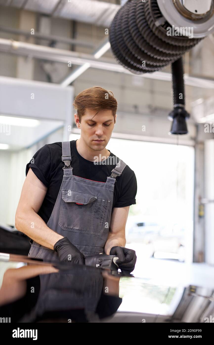 hard-working auto mechanic worker polishing car at automobile repair ...