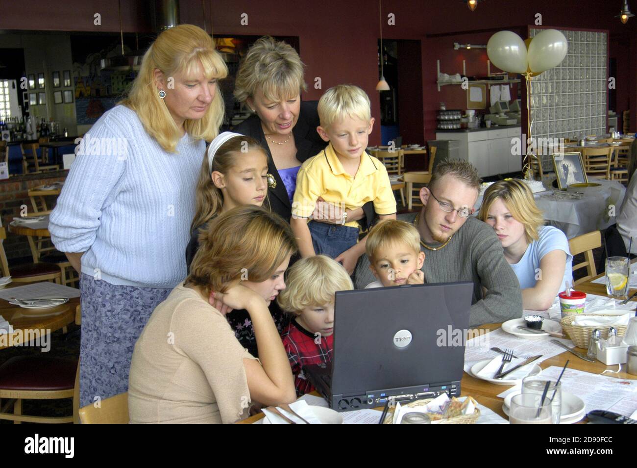 Family gathers around each other and a computer to look at family ...