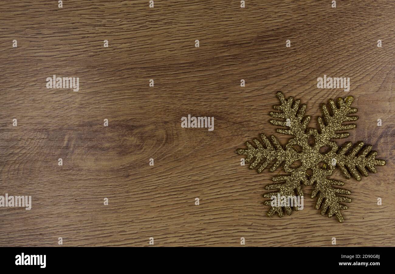 Gold color shiny snowflake decoration in corner on brown wood imitation ...