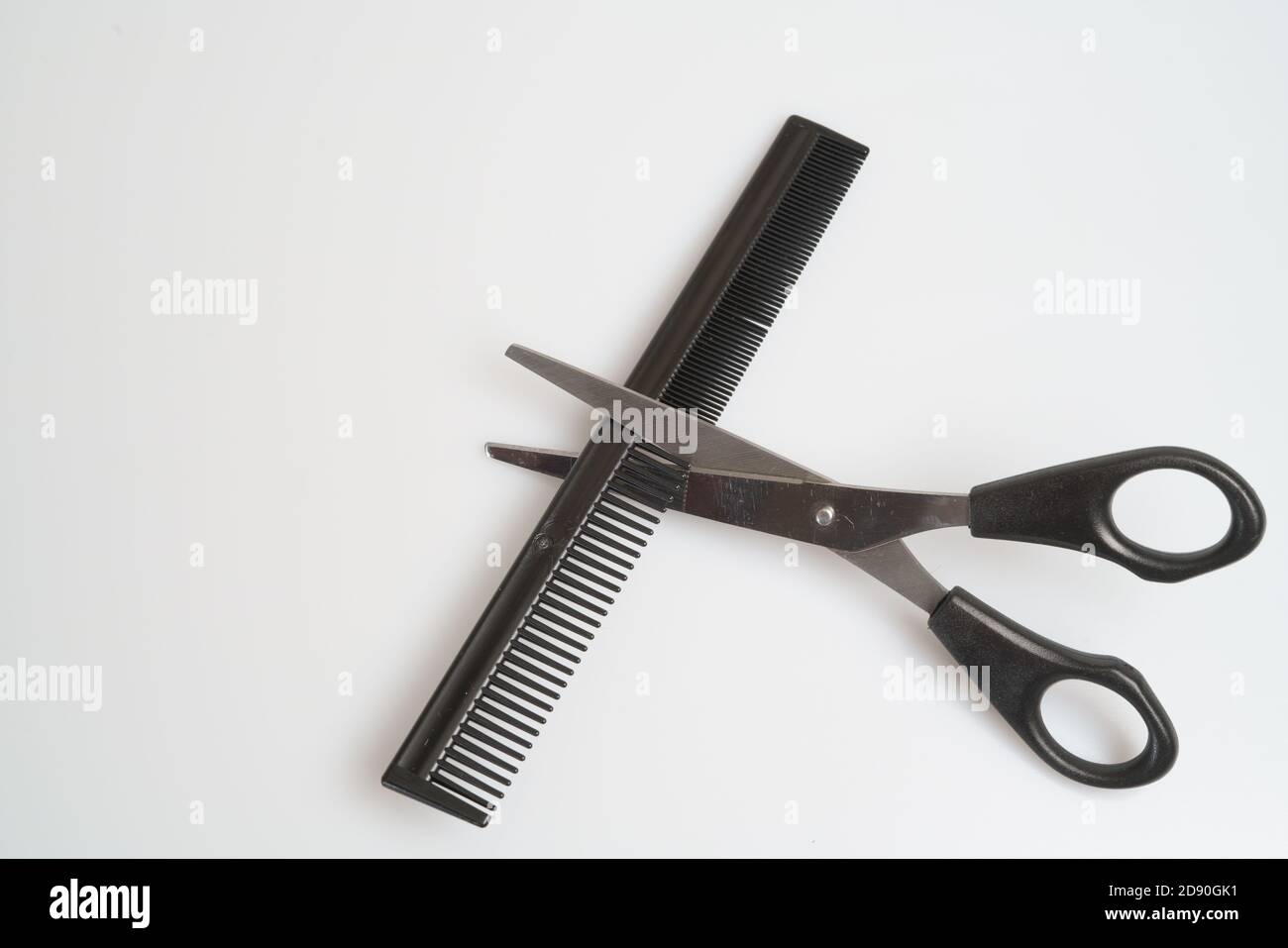stainless steel scissors with black handle lie and comb on a light ...