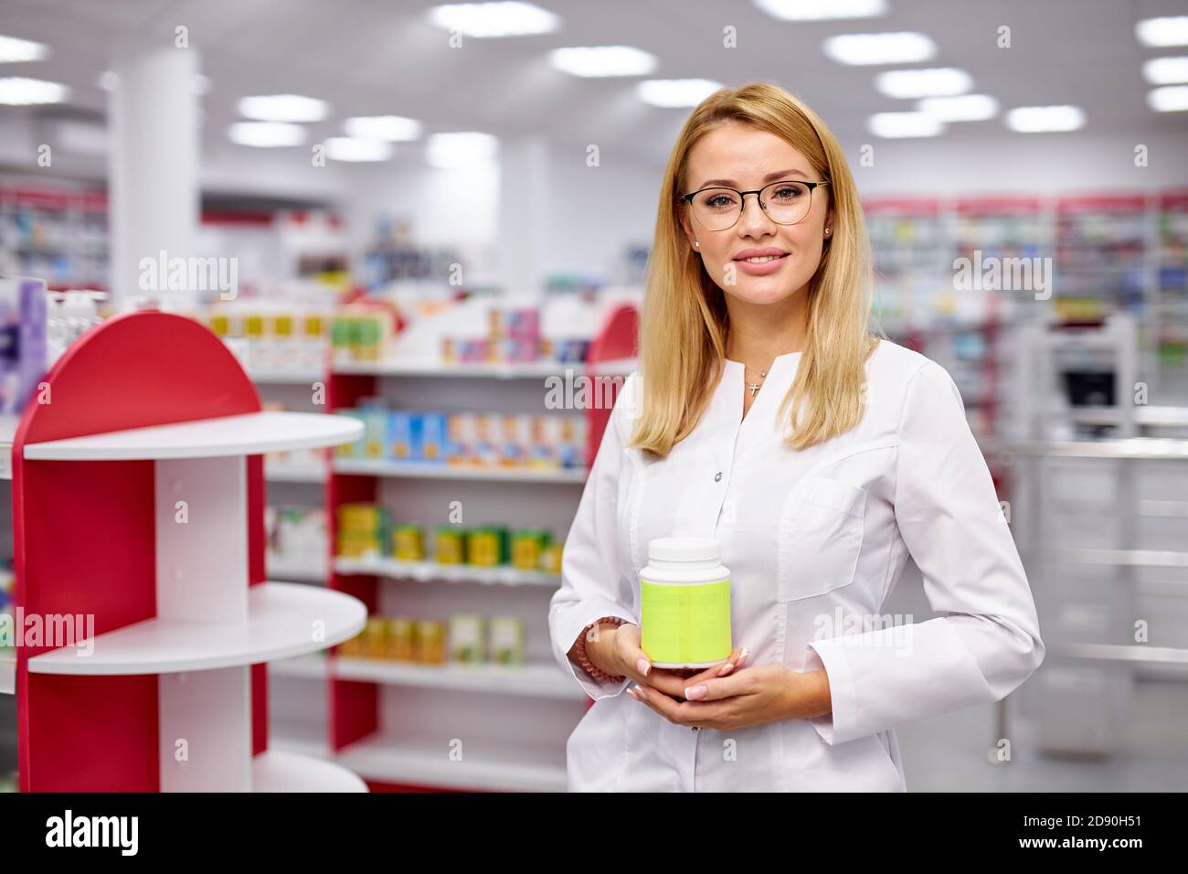 portrait of good-looking woman pharmacist with medicine container in ...