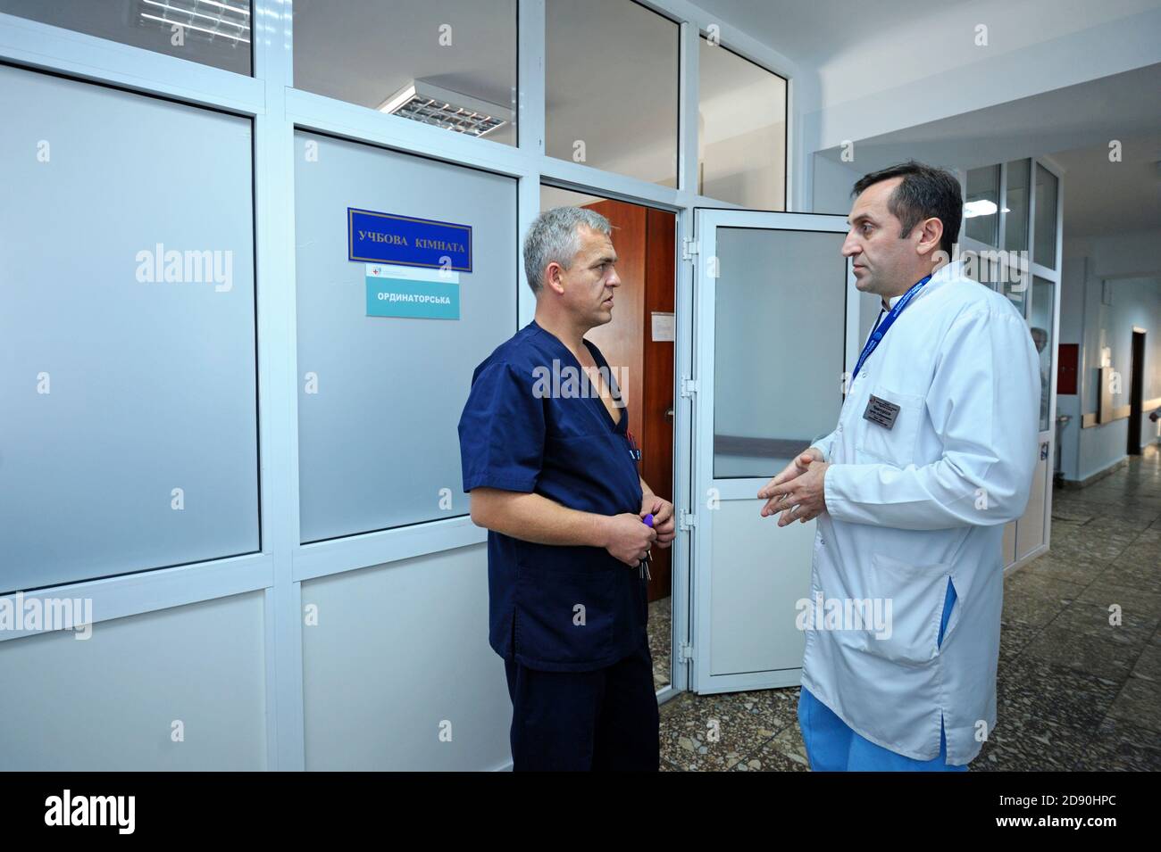 Two men in a lab coat standing at a corridor of the surgical unit and ...