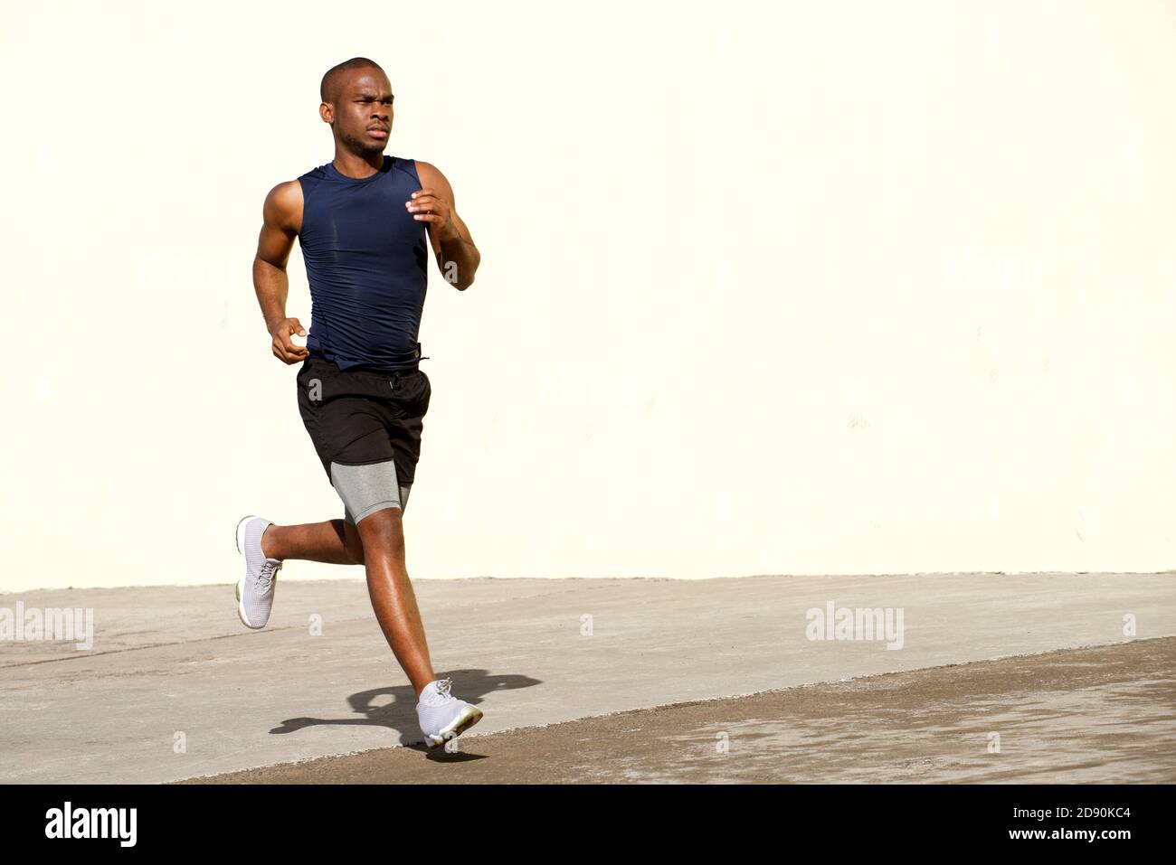 Full body portrait of healthy young black man running outside on street ...