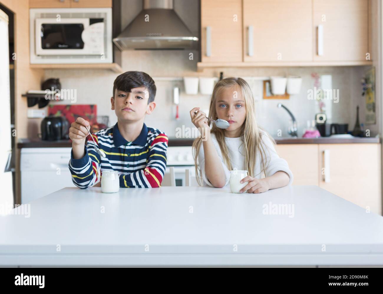 Happy children eating a yogurt in the dining room of their house Stock ...
