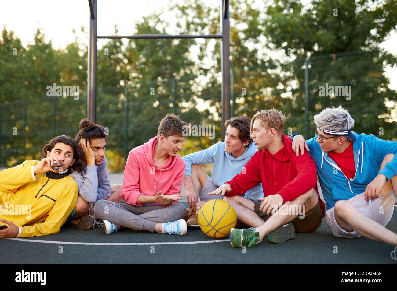 relaxed male teens have rest after sport games, basketball outdoors in ...