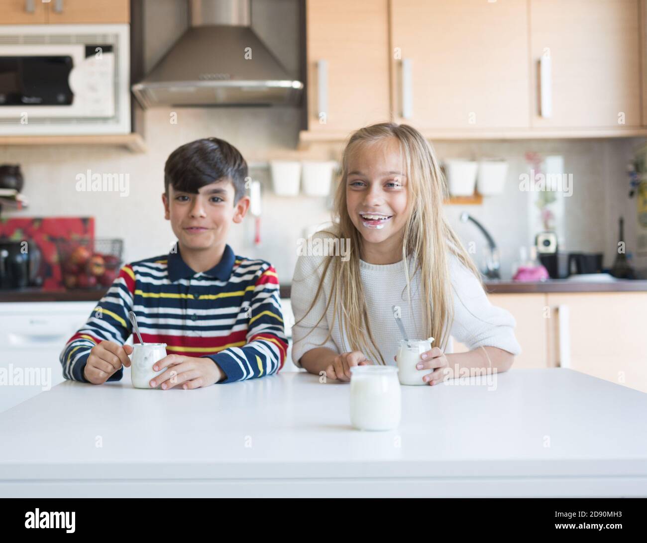 Happy children eating a yogurt in the dining room of their house Stock ...