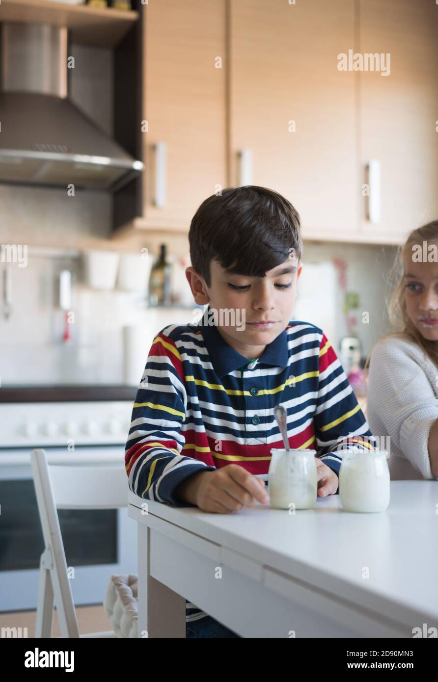 Happy children eating a yogurt in the dining room of their house Stock ...