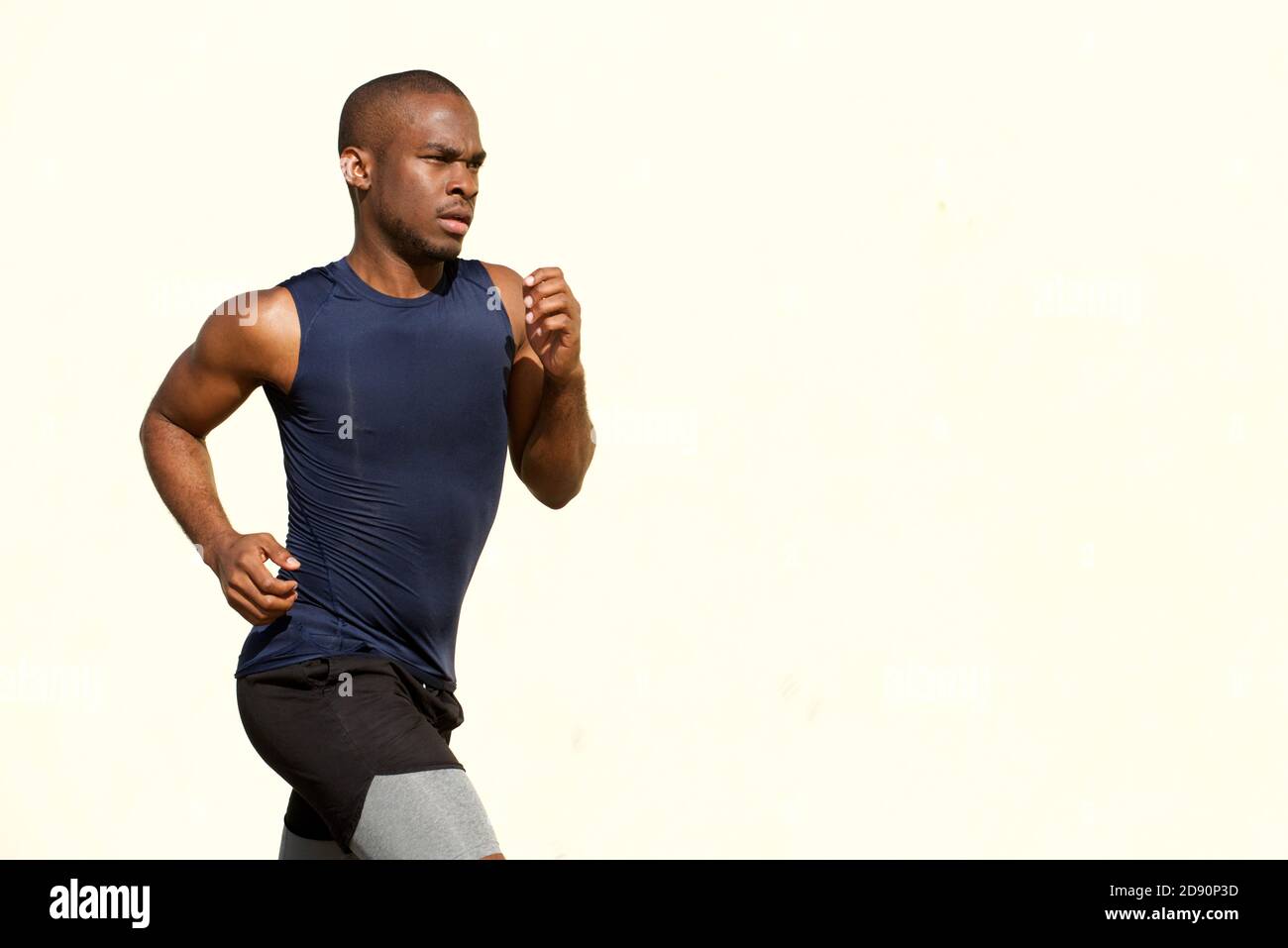 Side portrait of fit young black man running by white wall Stock Photo ...
