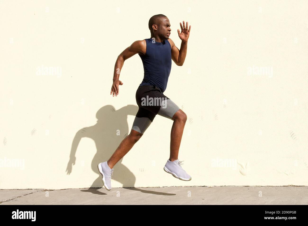 Full body side portrait of healthy young black man running by wall ...