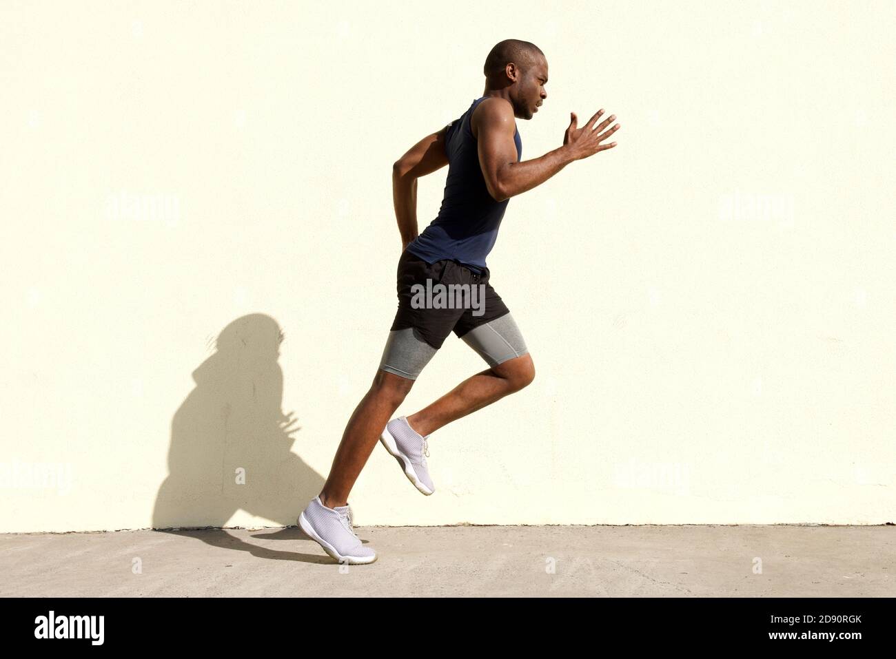 Full body profile portrait of healthy young black man running by wall ...