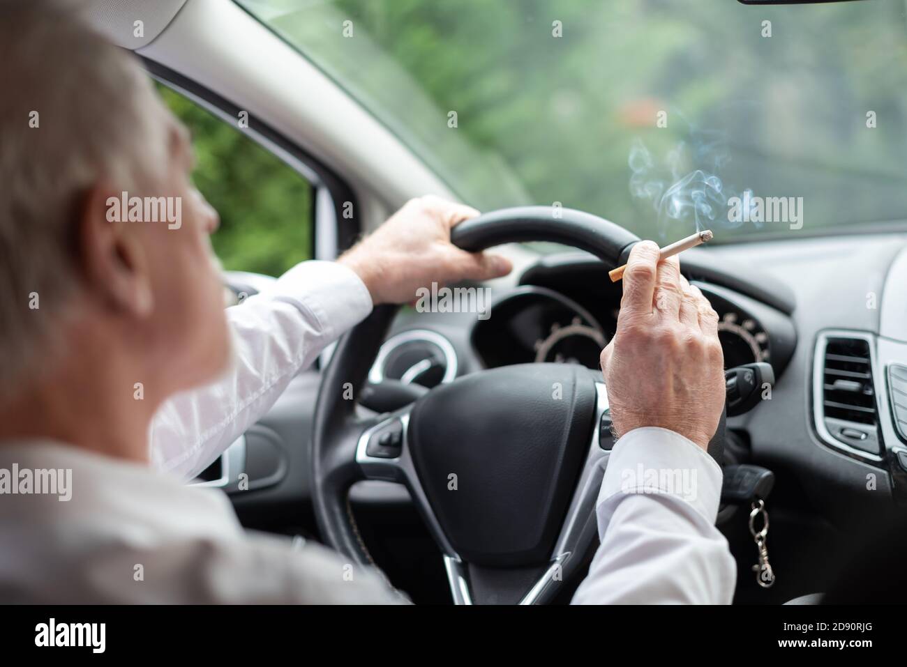 Senior man smoking a cigarette while driving Stock Photo - Alamy