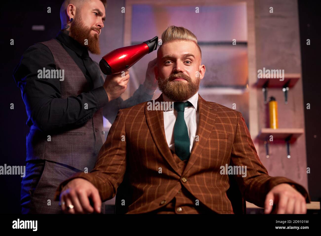 stylish man sitting in barber shop while hairdresser dry his hair ...