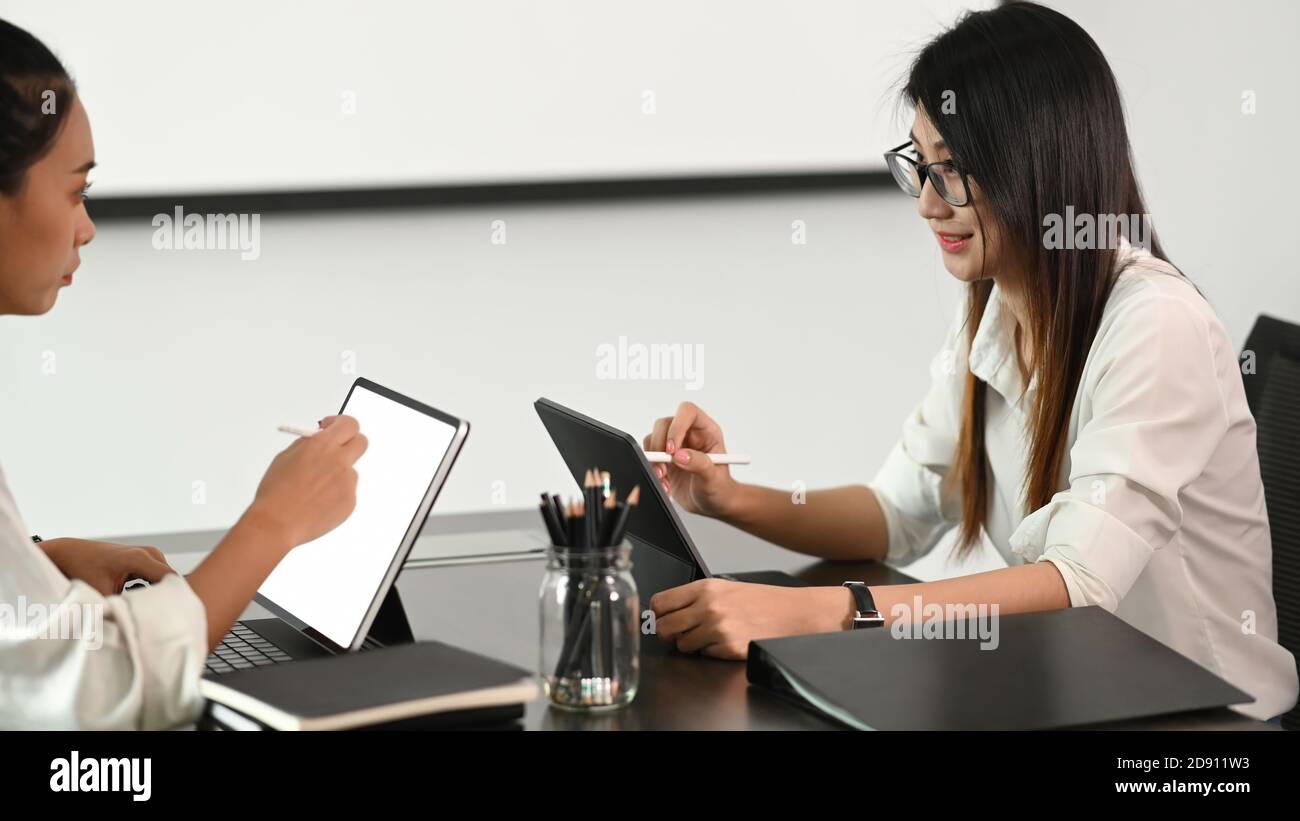 Two female hands using stylus pen pointing on digital tablet while ...