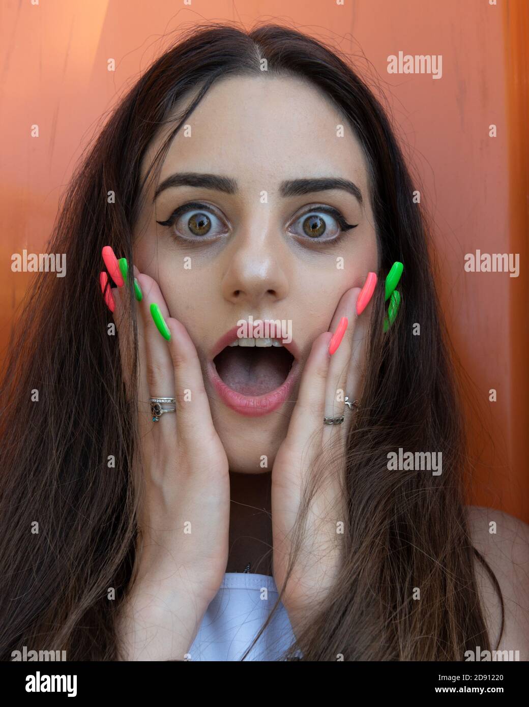 Shocked or surprised beautiful young woman holding her cheeks and ...