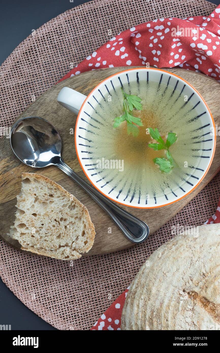hot bone broth in a white soup bowl served with parsley herb and ...