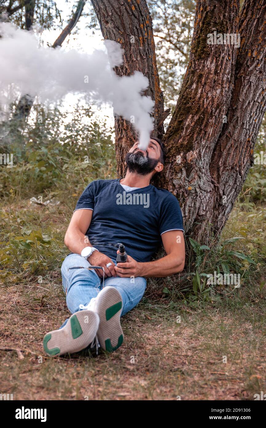 Stylish vaper in the fresh air smoking an electronic cigarette. Vaping ...