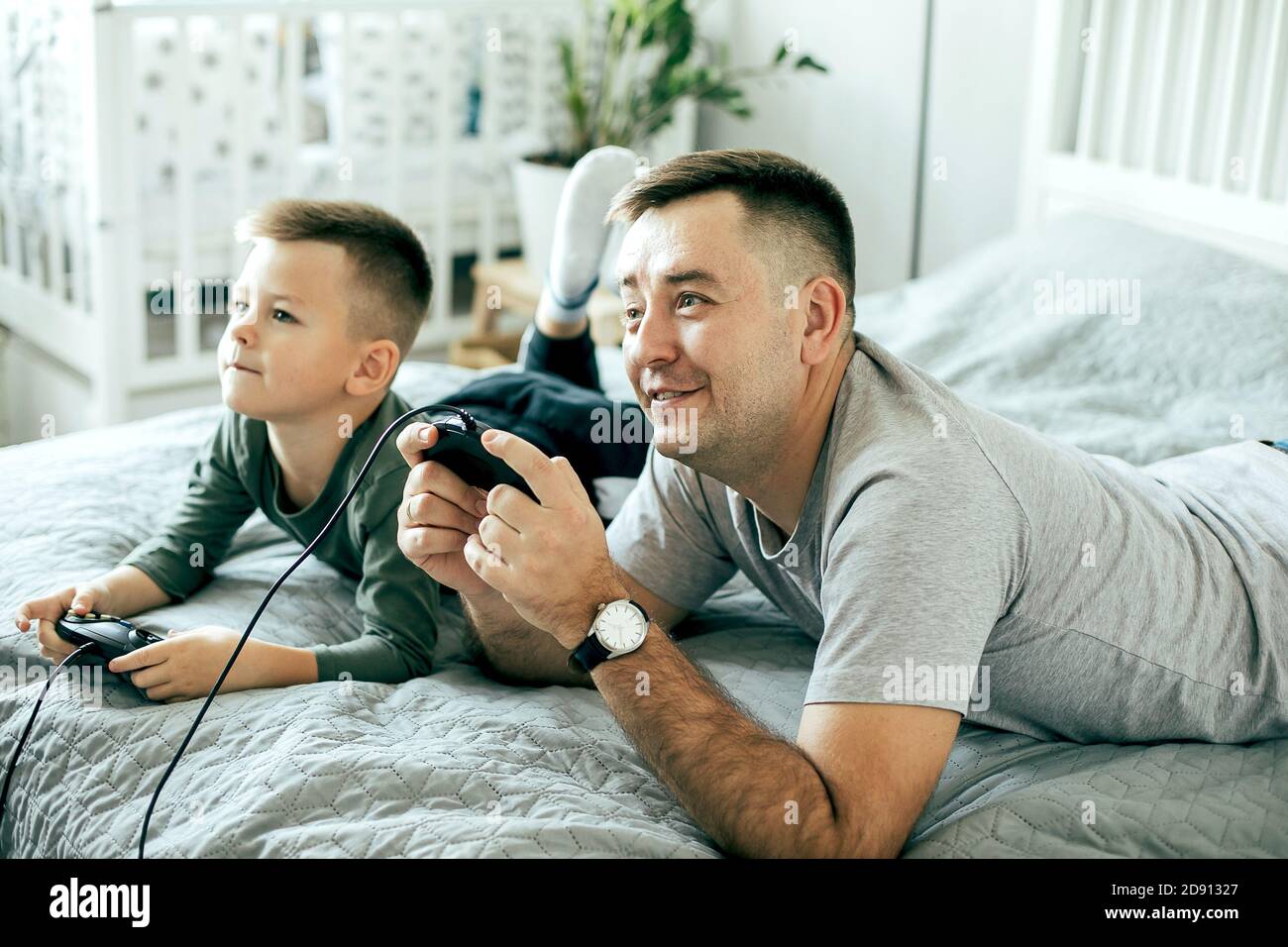 Smiling family son and dad playing video games and having fun together ...