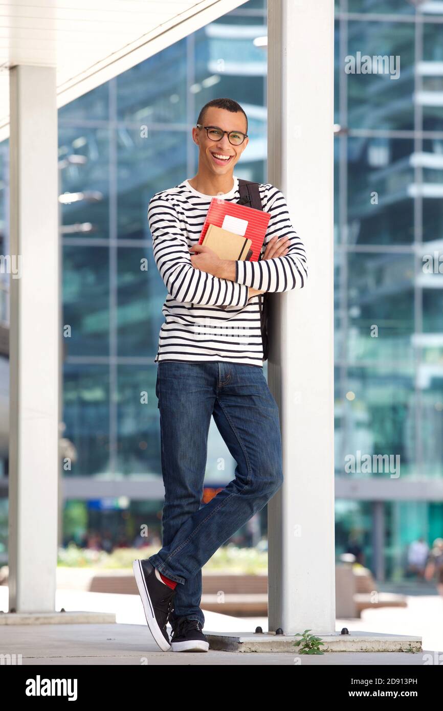Full body portrait of smiling male college student standing at campus ...