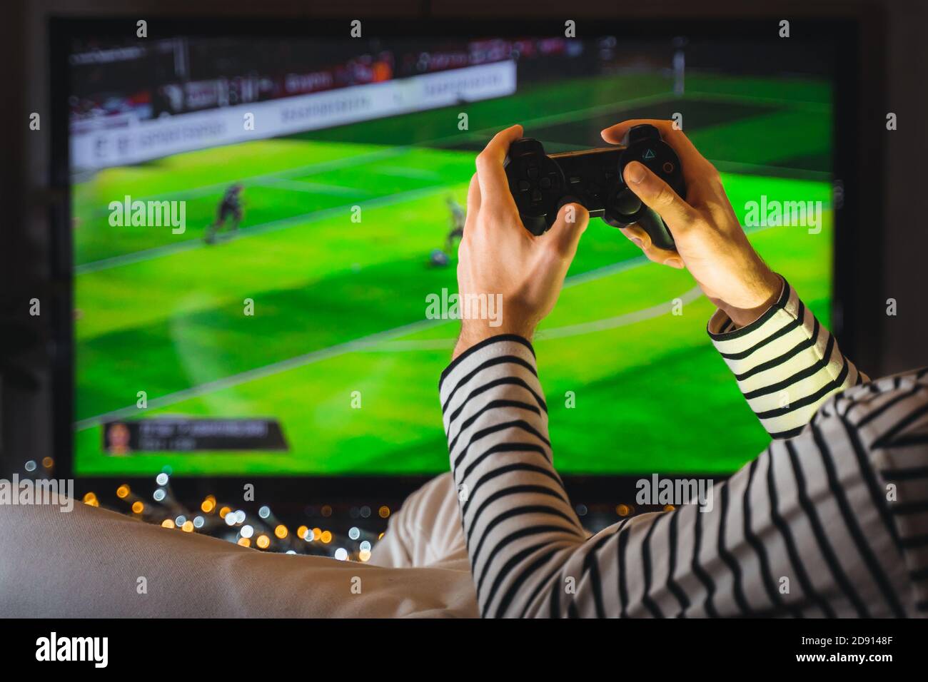 Young hipster man playing video game football soccer on console. gamer ...