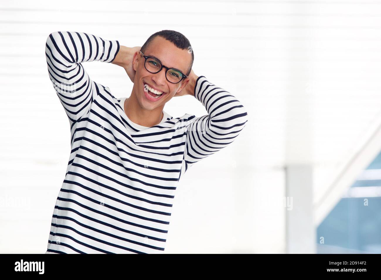 Portrait of cheerful young man laughing with hands behind head Stock ...