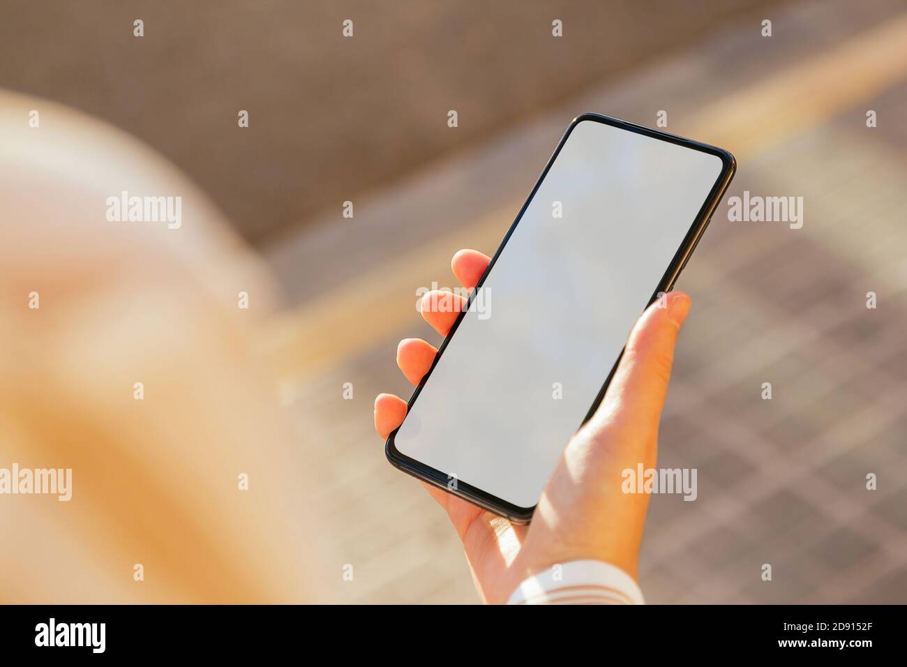 Phone mockup held by a woman's hand who is on the street. Mobile phone ...