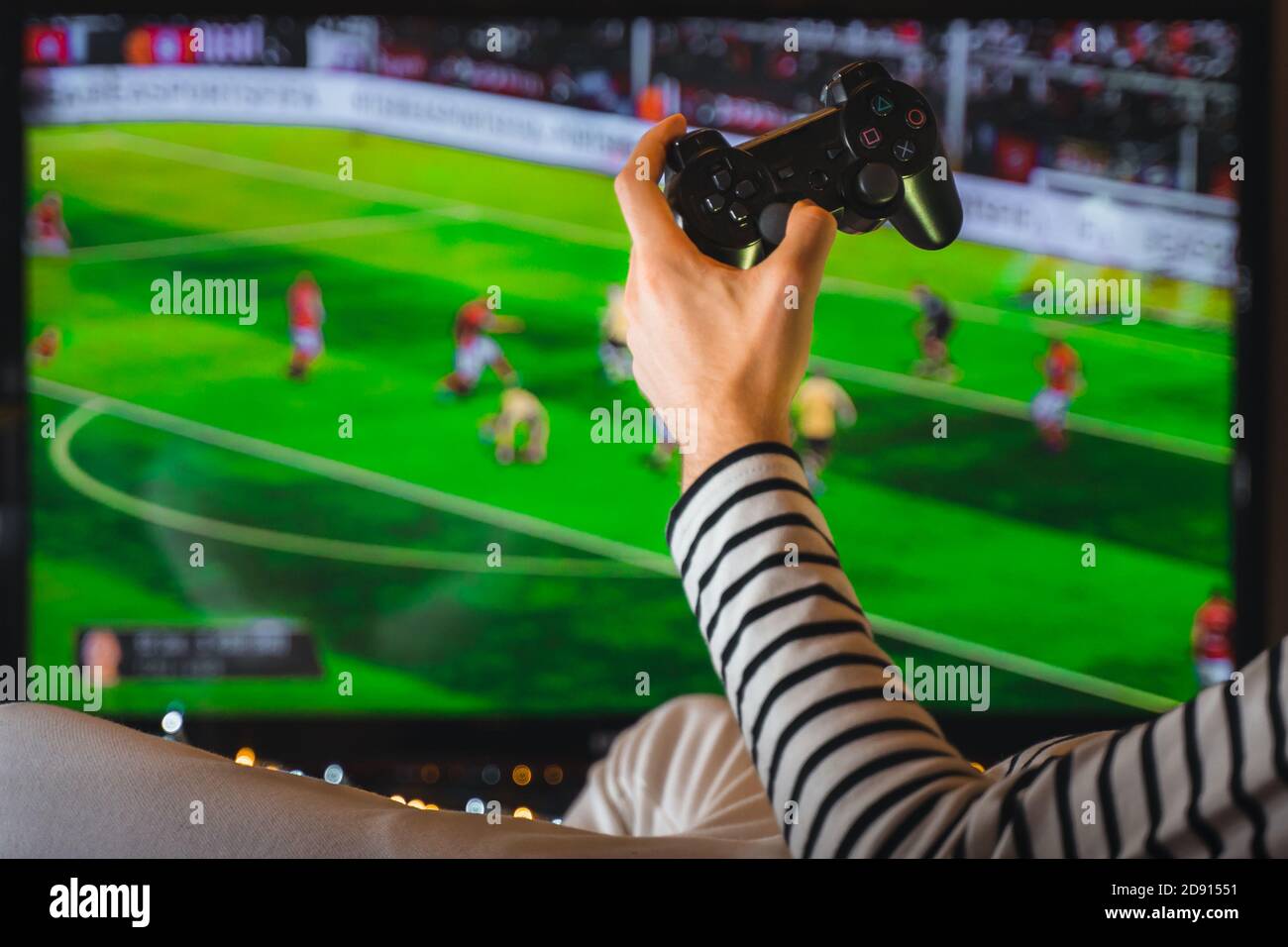 Young hipster man playing video game football soccer on console. gamer ...