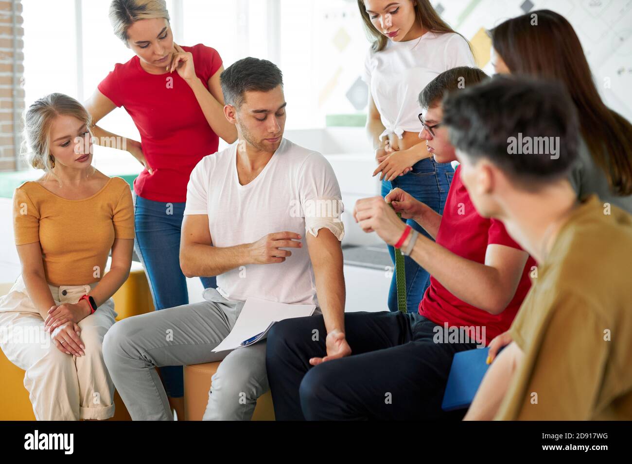 group of young caucasian people practice treating a patient by bandages ...