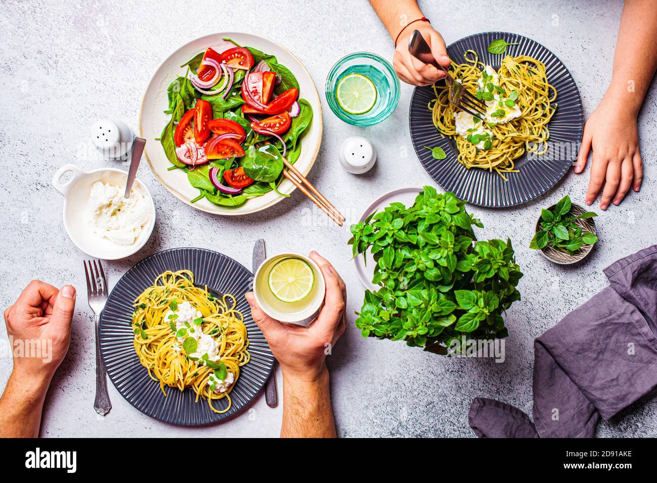 Family lunch table, top view. Peoples hands eating italian pasta with ...