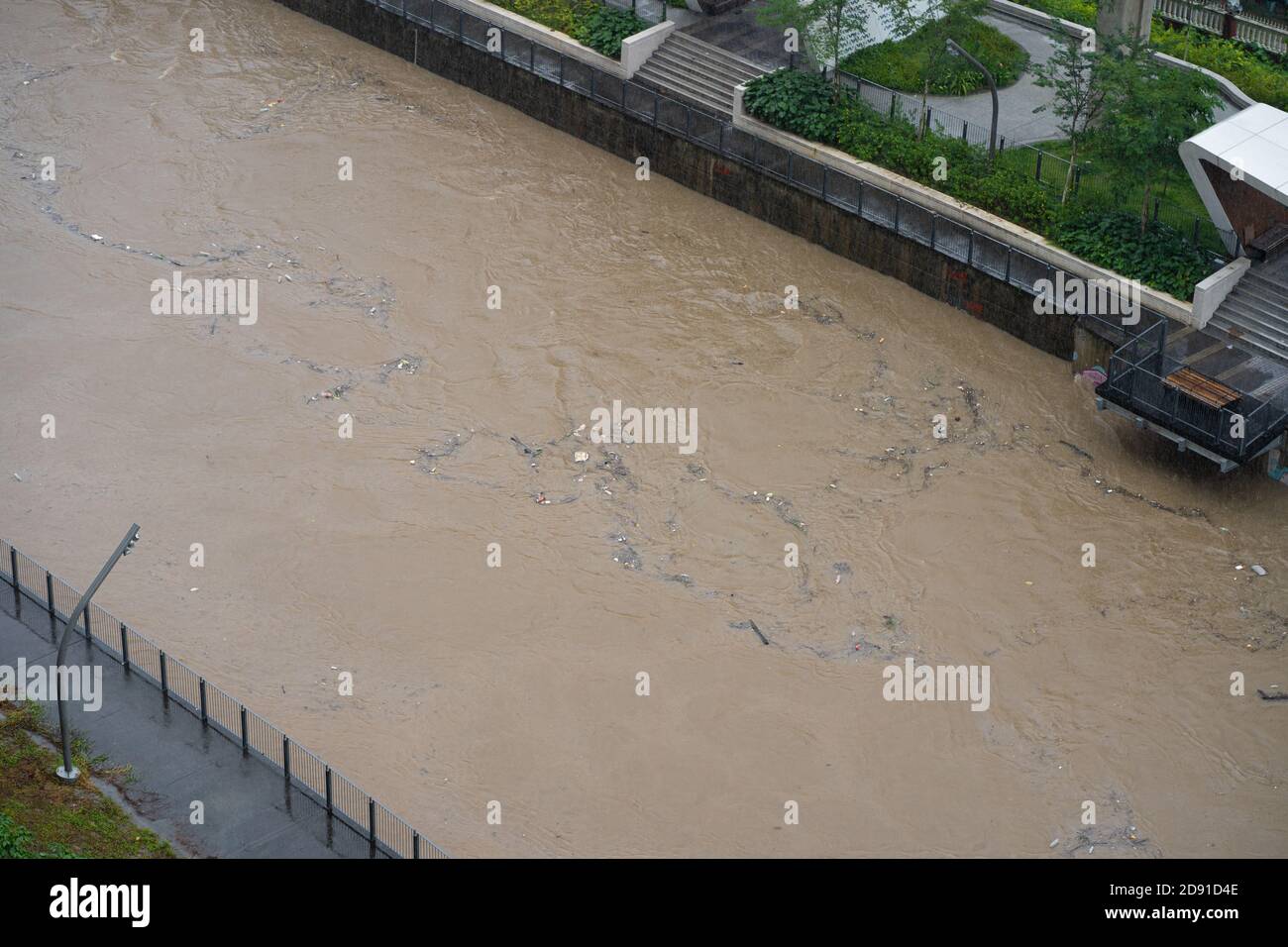 River canal in a big city. Sewage after rain carries garbage along the ...