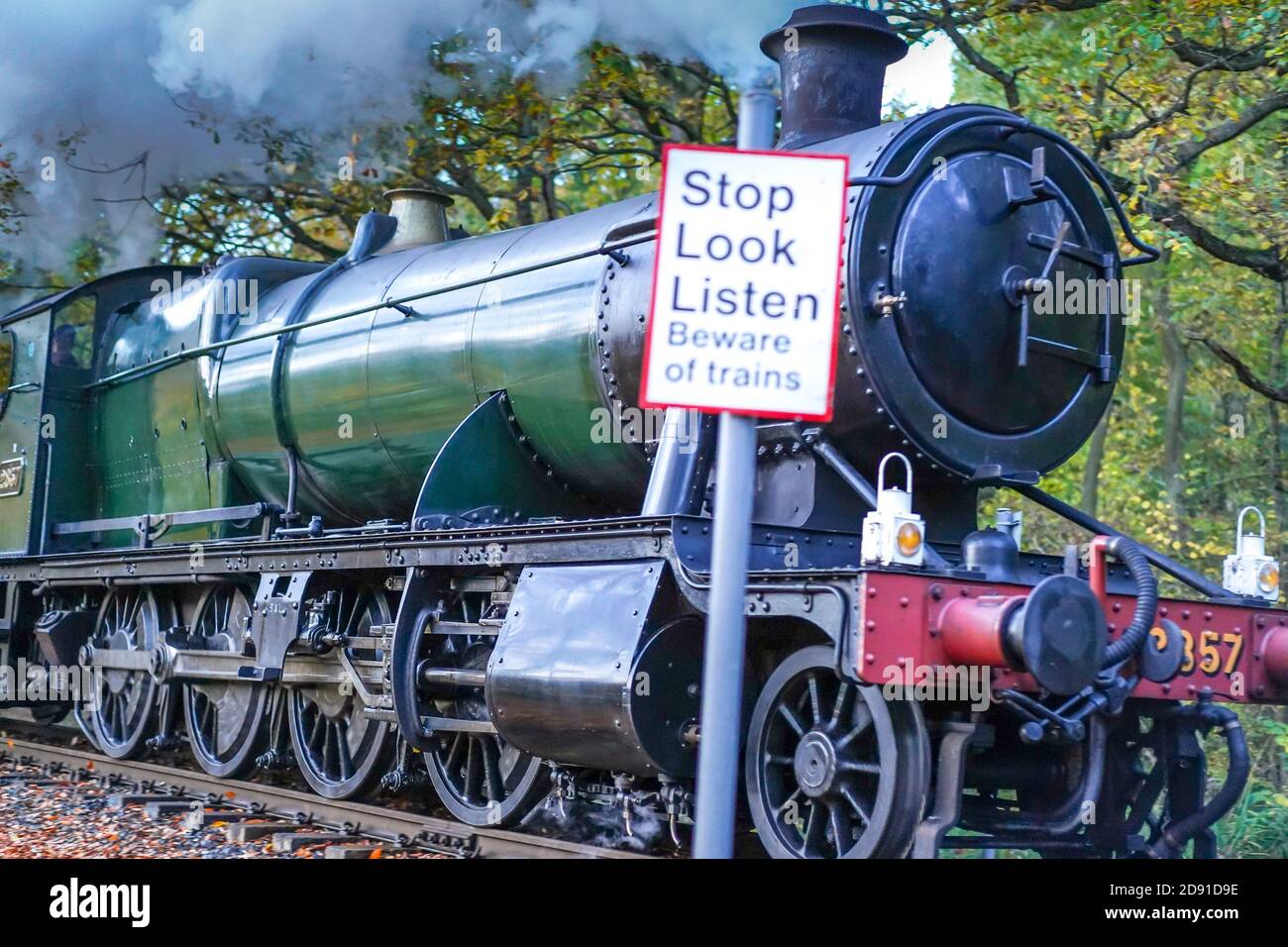 Vintage UK steam train passing Stop Look Listen danger sign on rural ...