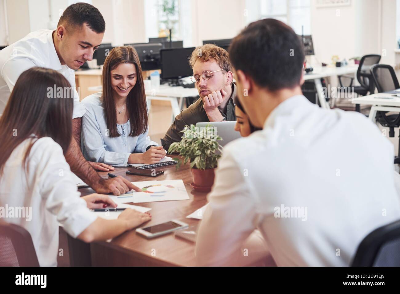 Young business people sitting by the table, talking and working ...