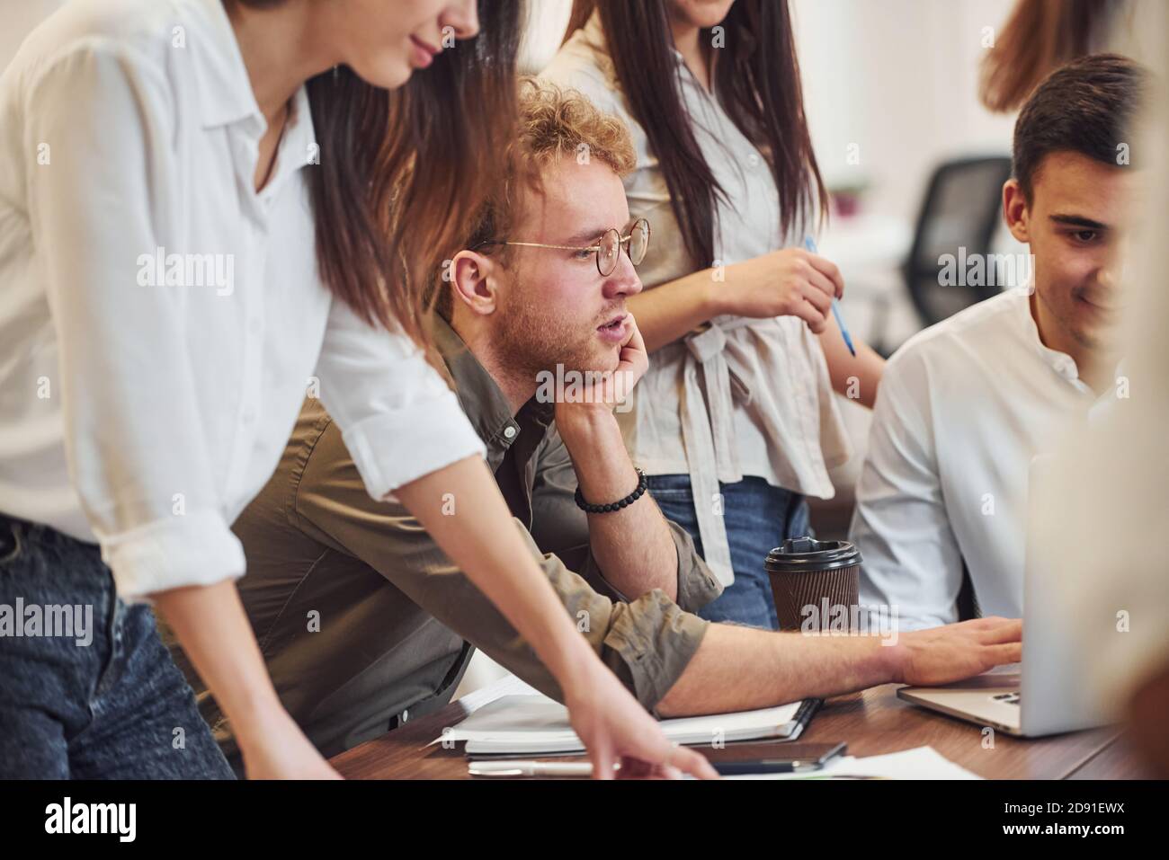 Young business people sitting by the table, talking and working ...