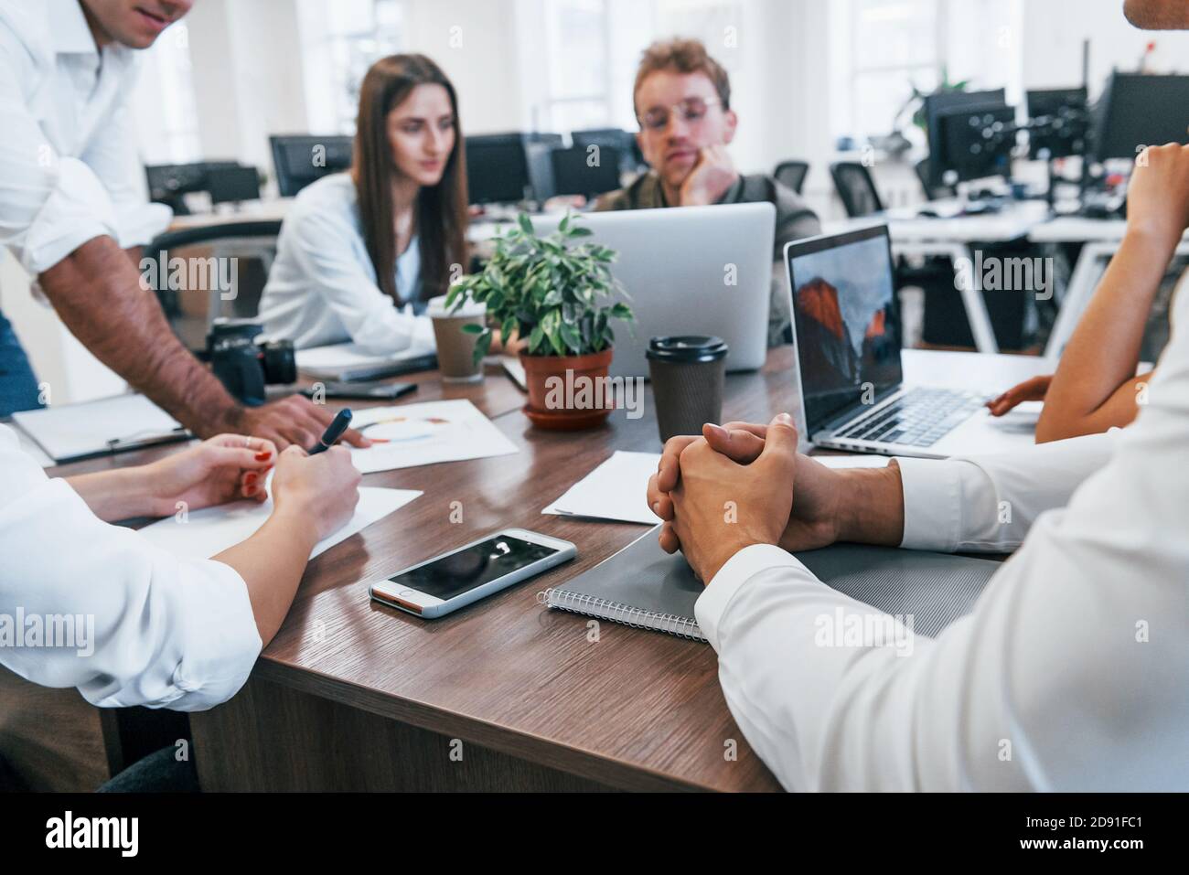 Young business people sitting by the table, talking and working ...