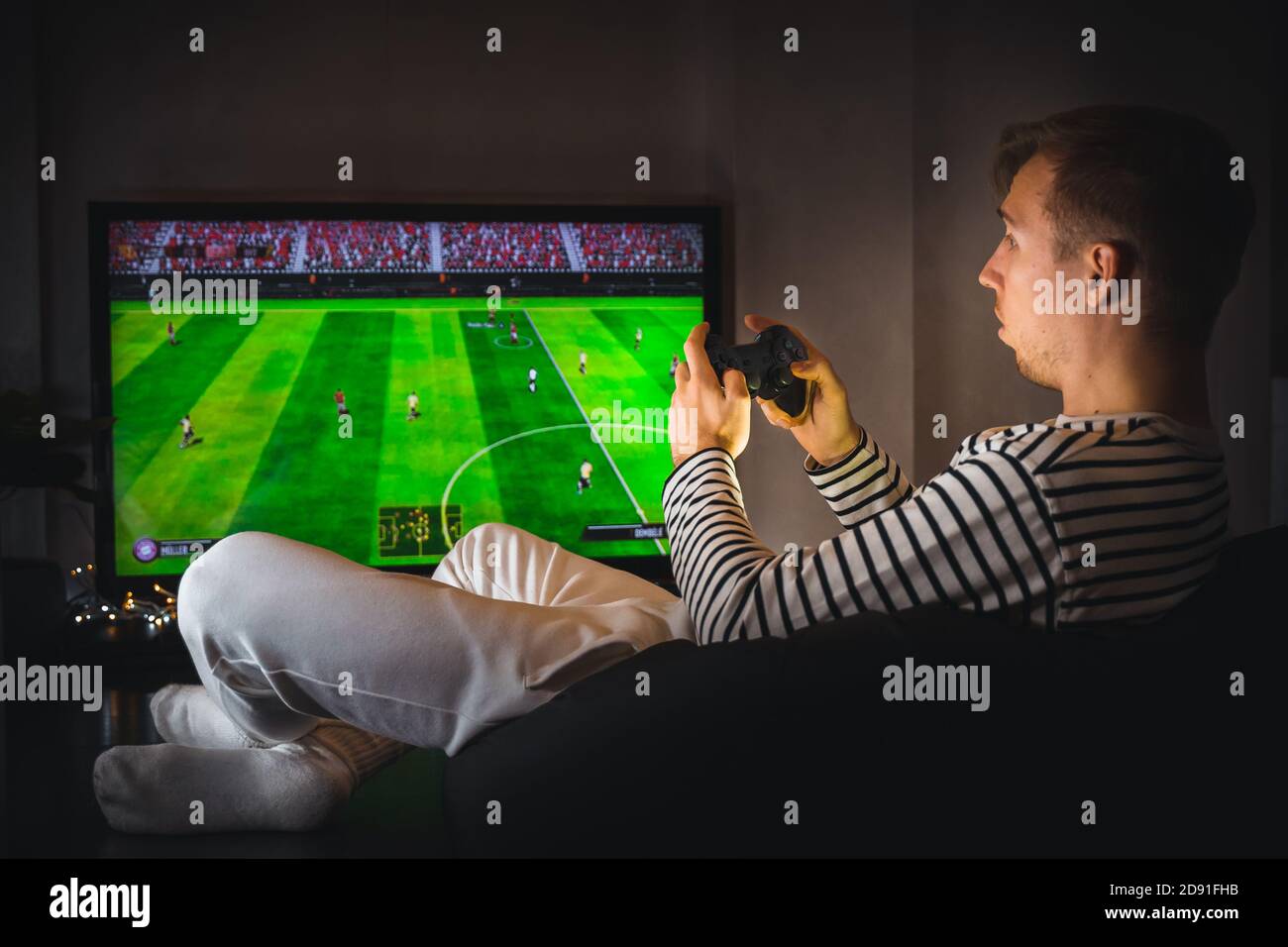 Young hipster man playing video game football soccer on console. gamer ...